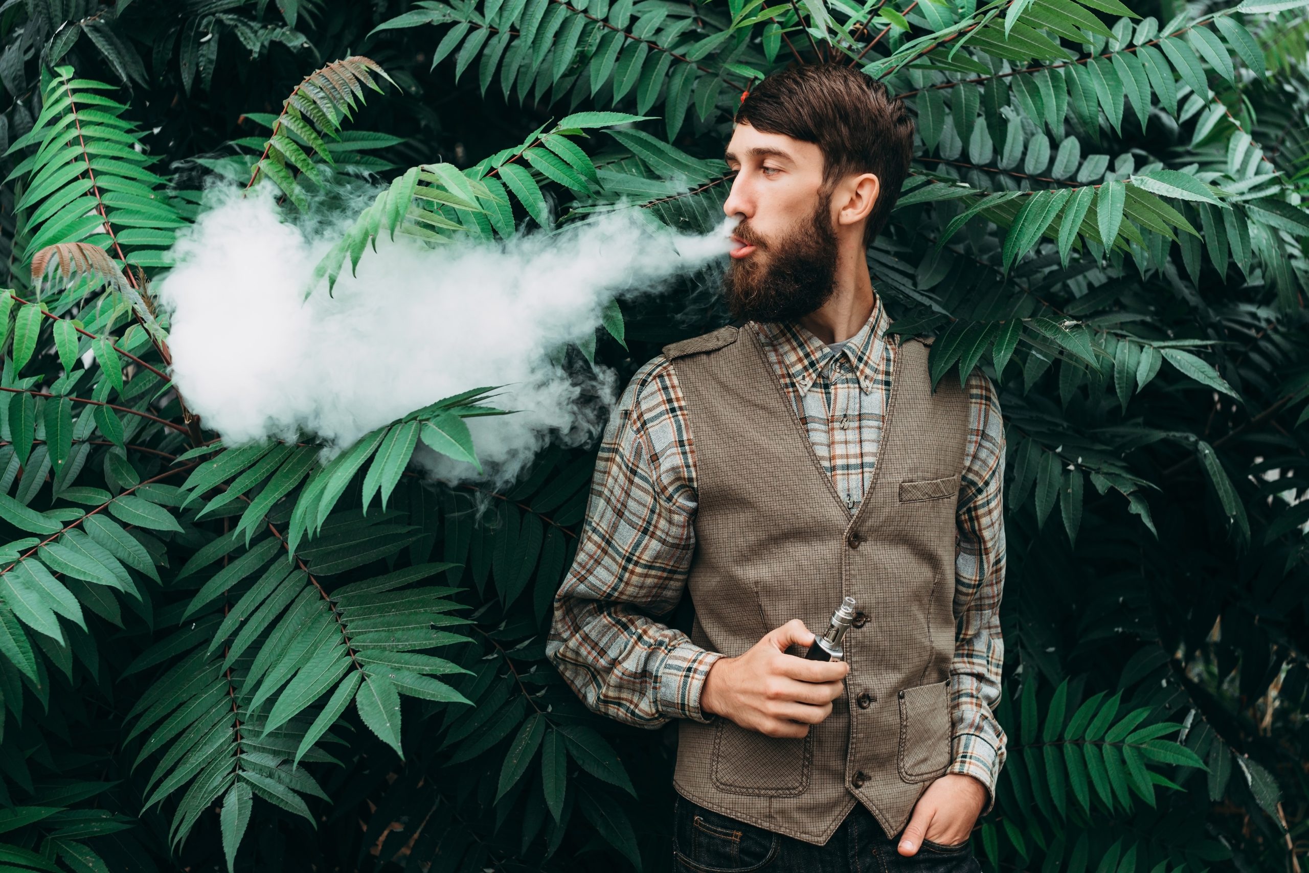 Young man with beard vaping an electronic cigarette outdoor. hipster ...